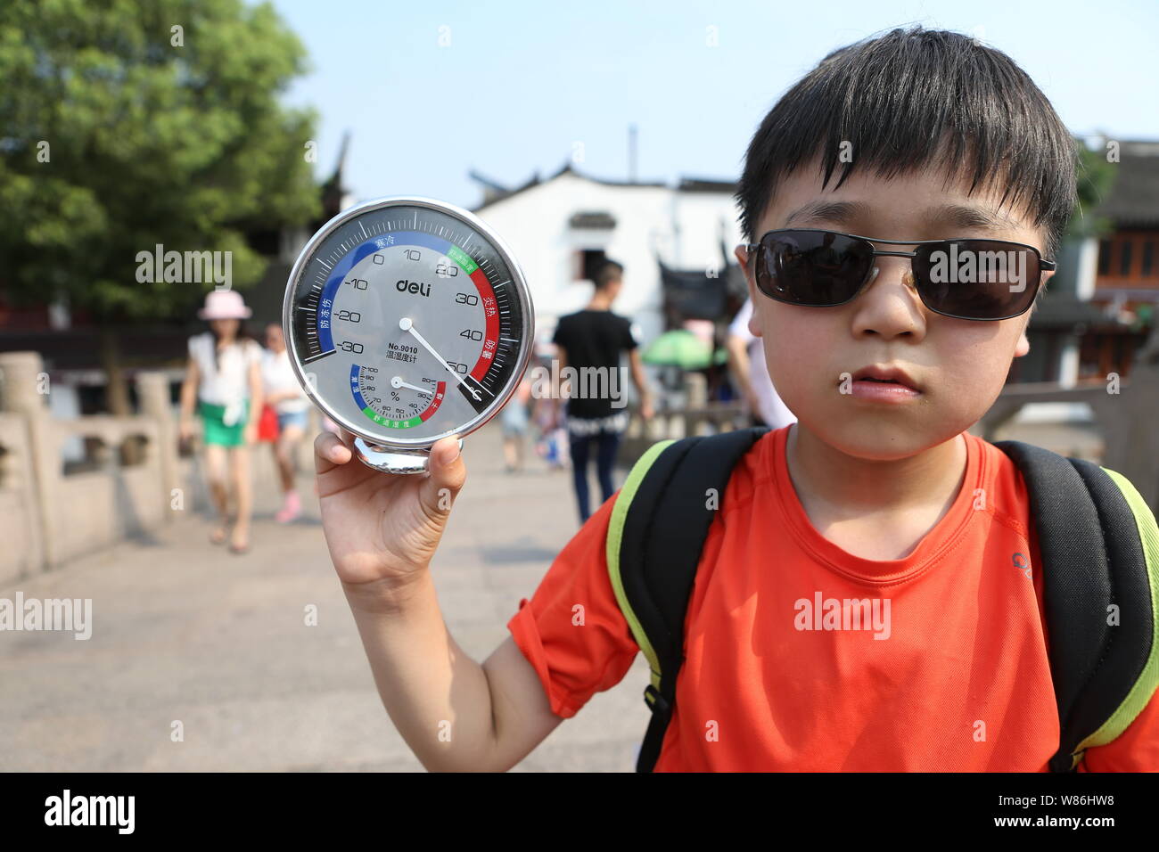 A young boy displays a thermometer showing the current temperature ...