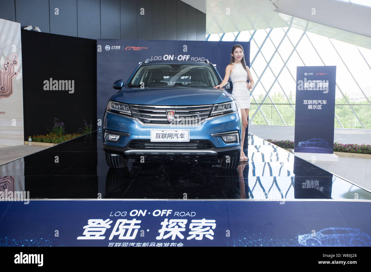 A model poses with a Roewe RX5 SUV of SAIC Motor featuring Alibaba's YunOS at a launch event in ...