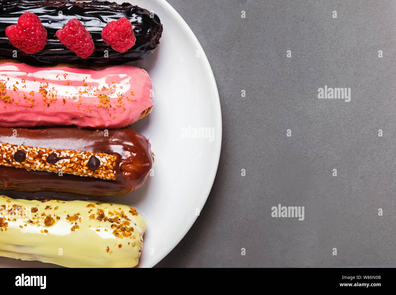 Delicious eclairs of different flowers on grey stone background with ...