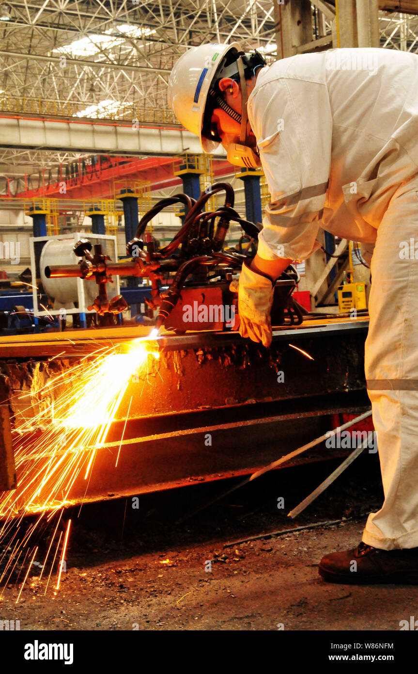 A Chinese worker processes steel at a factory in Qingdao city, east ...