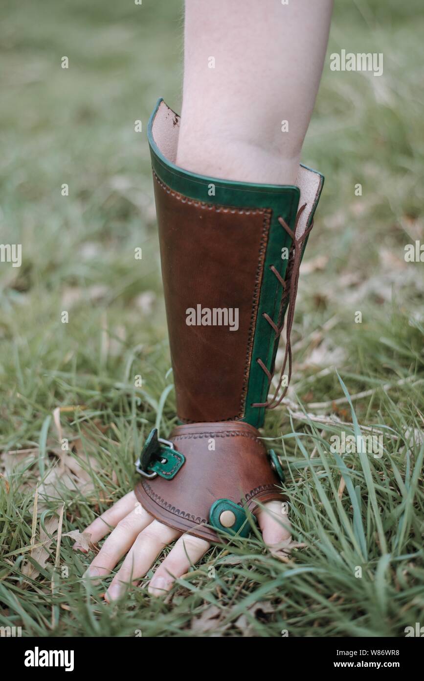 Closeup shot of a person wearing hand armor with the palm put on grass ...
