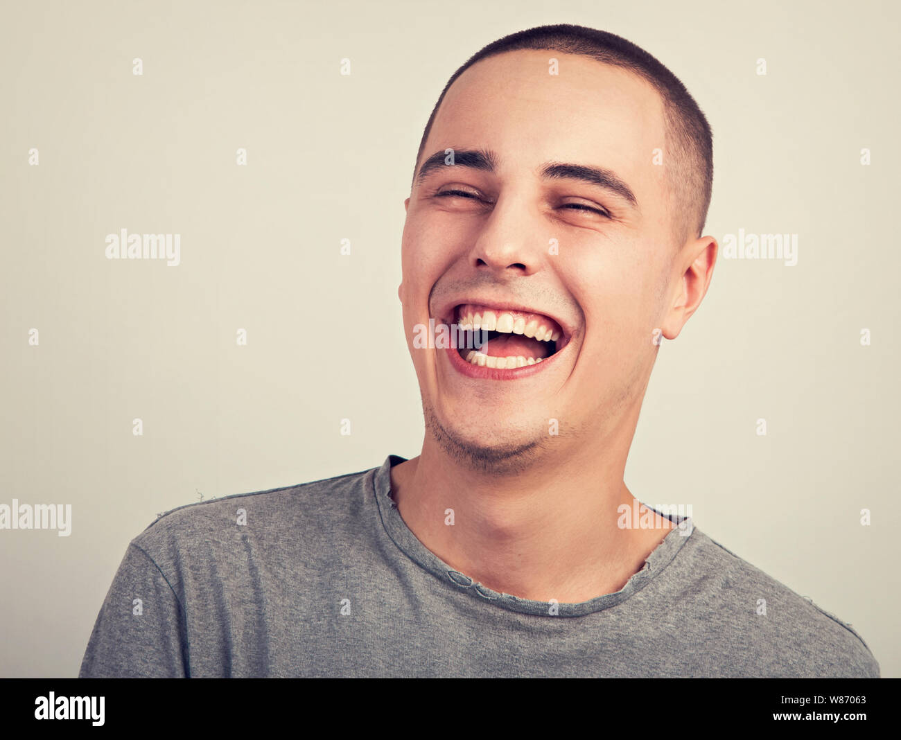 Happy fun young man laughing in casual clothing on grey background with ...