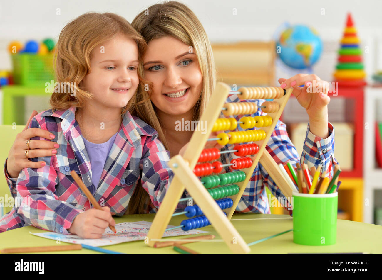 Portrait of mother teaching her daughter to use abacus indoors Stock ...