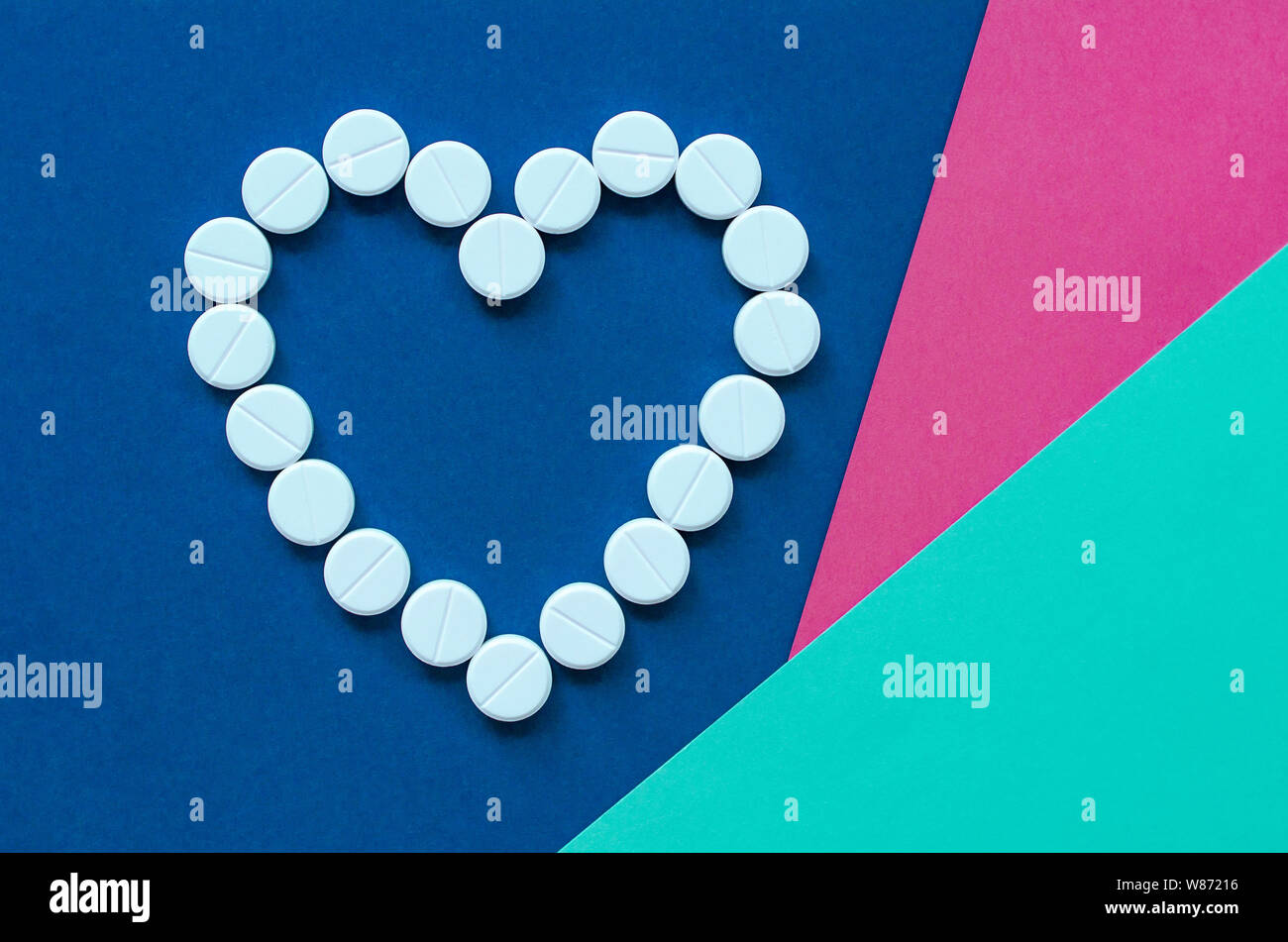 The white heart pills on a colored background. The concept of a healthy ...