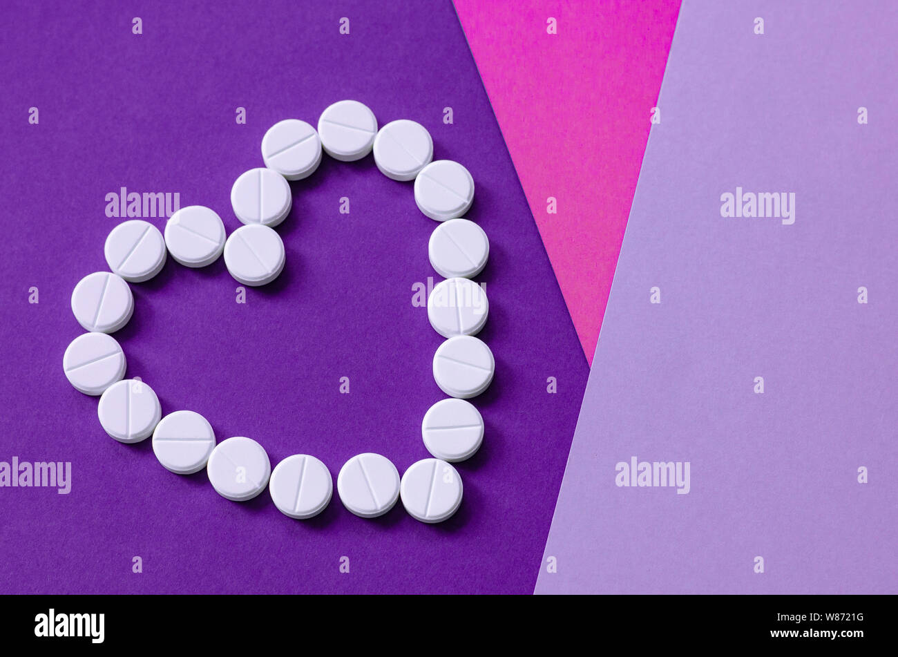 The white heart pills on a colored background. The concept of a healthy ...