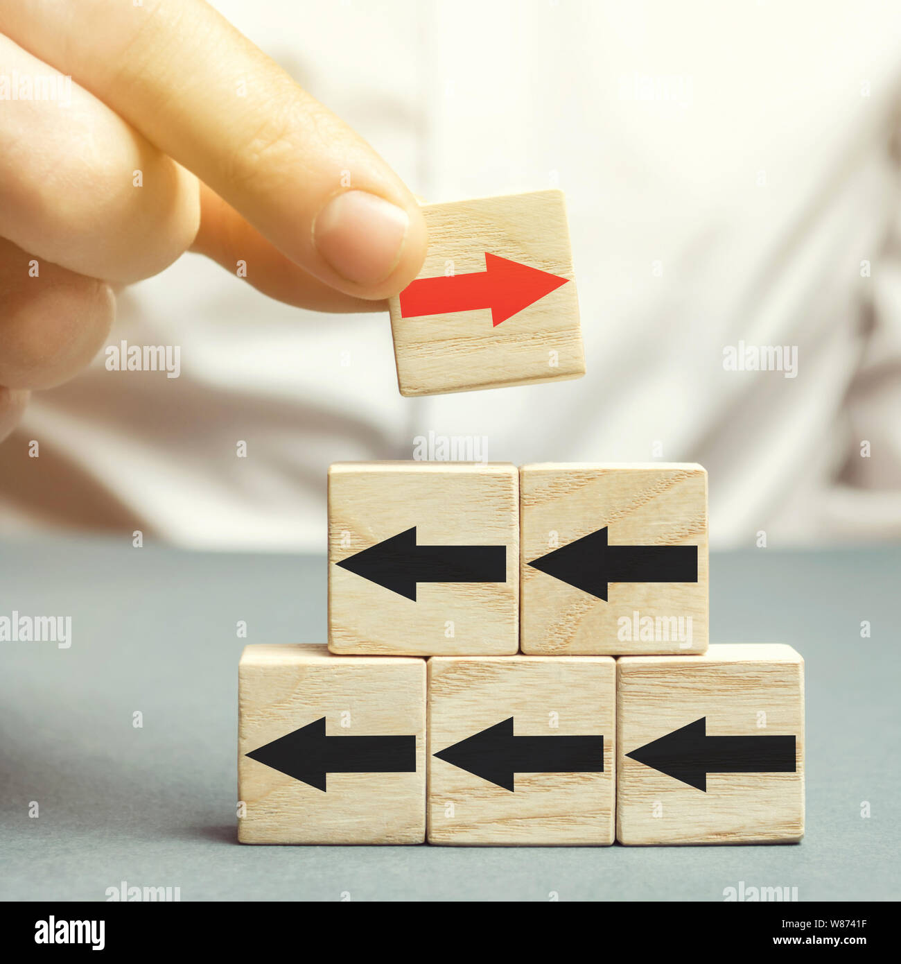 A man holds a wooden block with red arrow facing the opposite direction ...