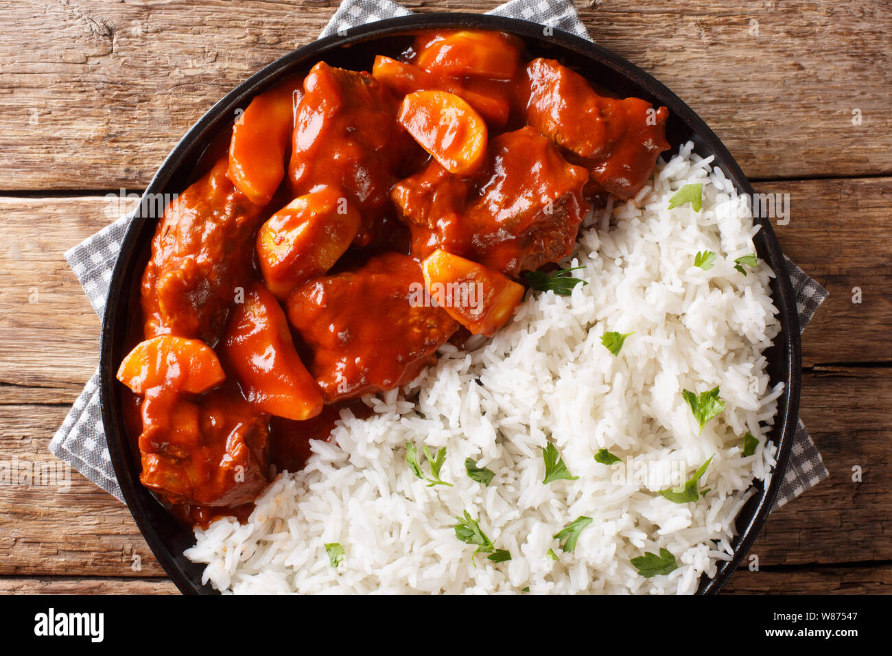 Serving of beef stew with apples in tomato sauce with rice side dish ...