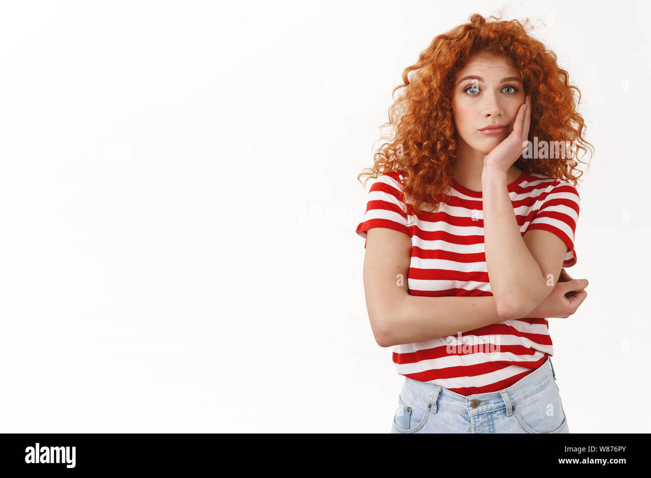 Bored indifferent young sad redhead curly woman blue eyes lean head ...