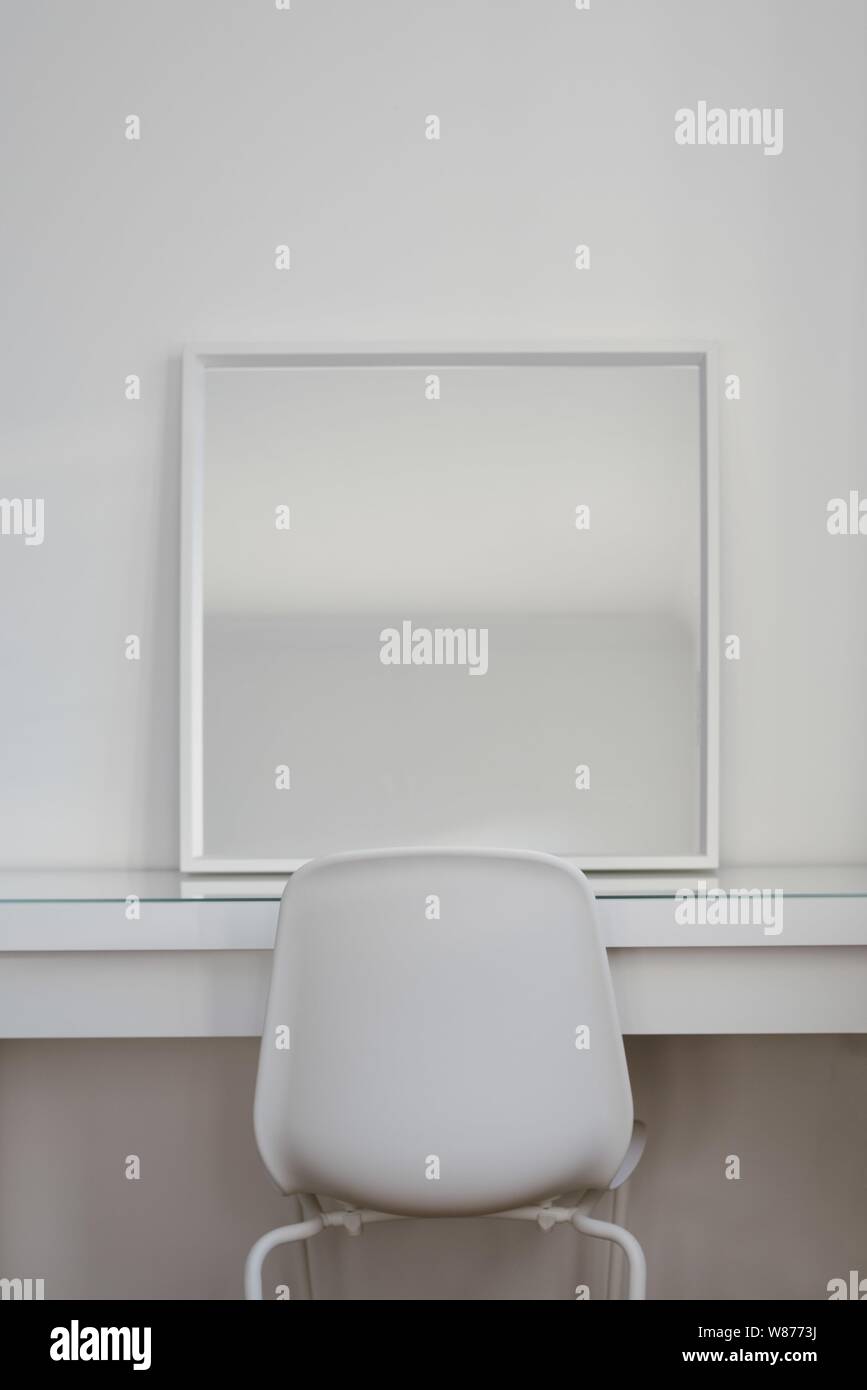 Vertical shot of a mirror on a white table with a chair in front Stock ...