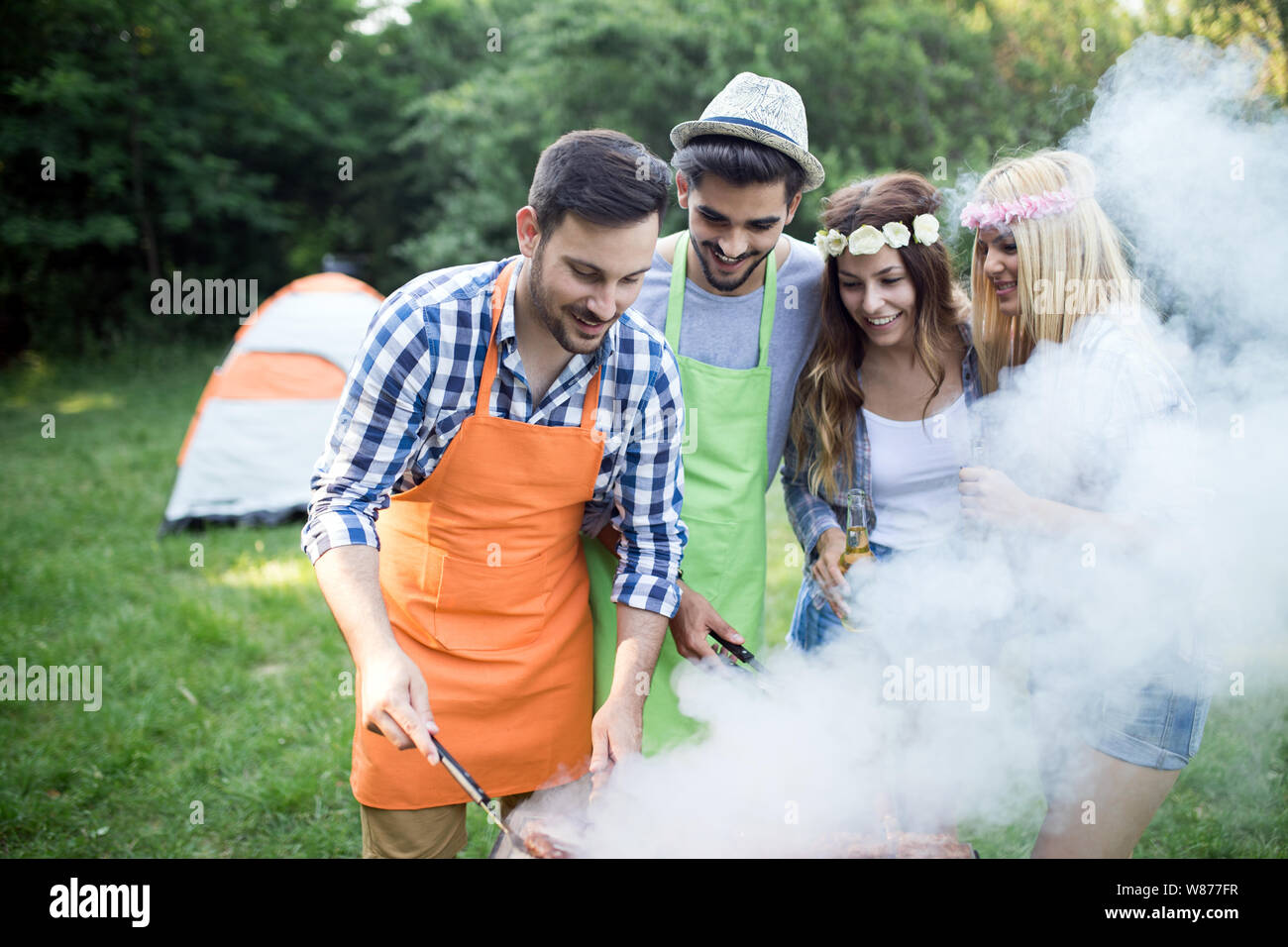 Group of friends making a barbecue together outdoors in the nature ...