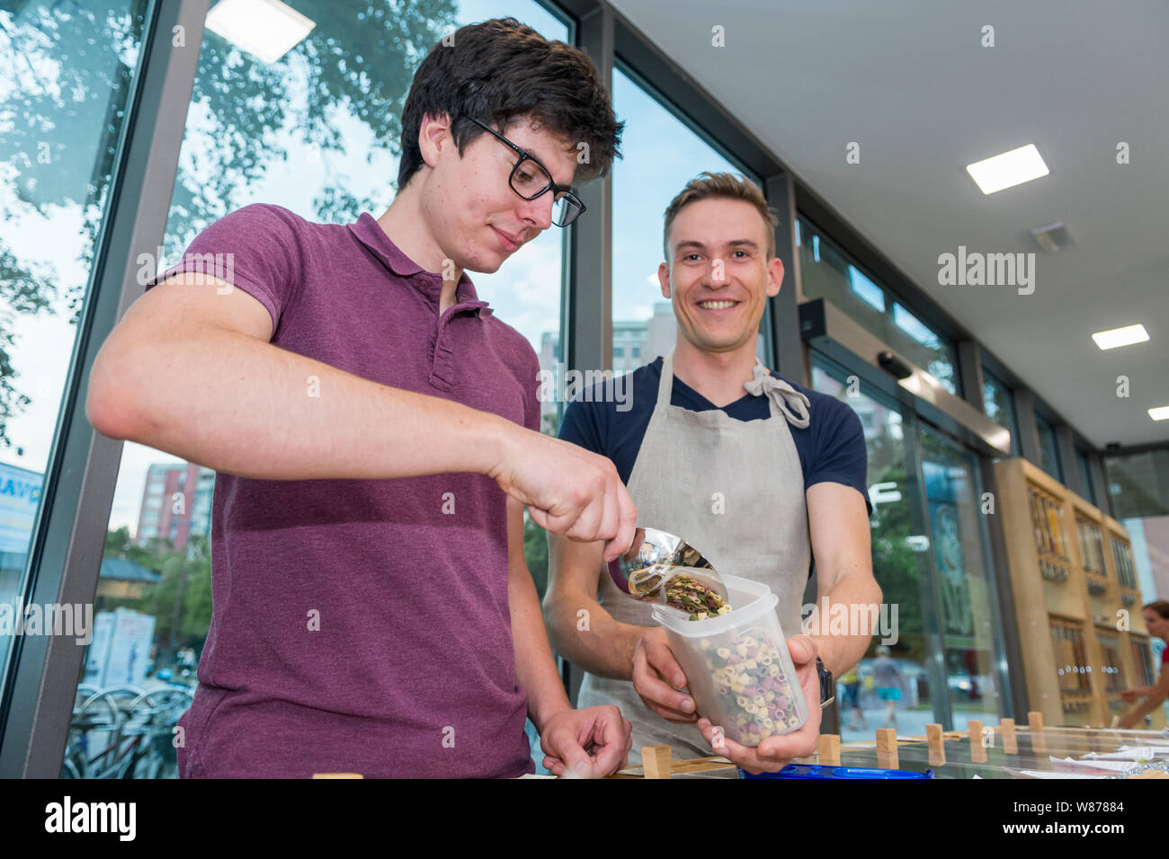 Male shopkeeper helping a customer in zero waste store Stock Photo - Alamy