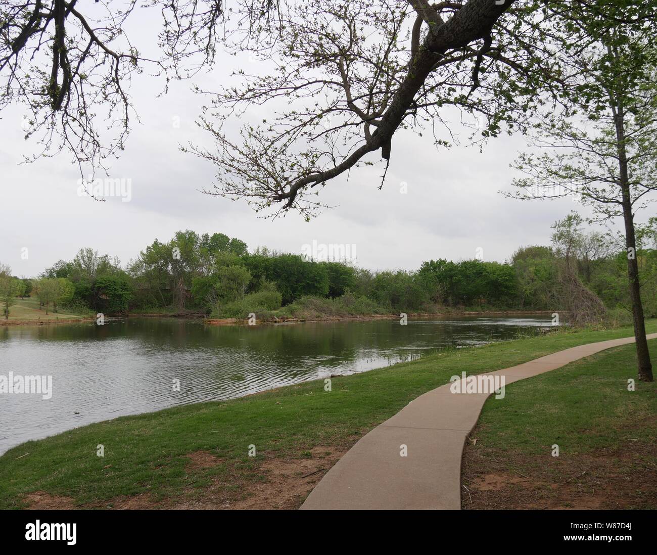 Nature view of a lake with a concrete walkway for joggers Stock Photo ...