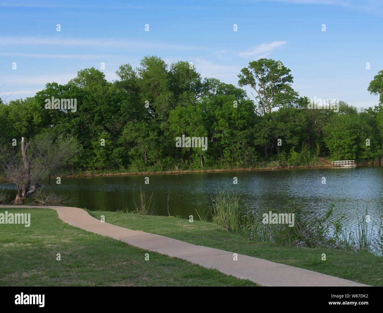 Scenic refreshing view of a lake with a concrete walkway Stock Photo ...