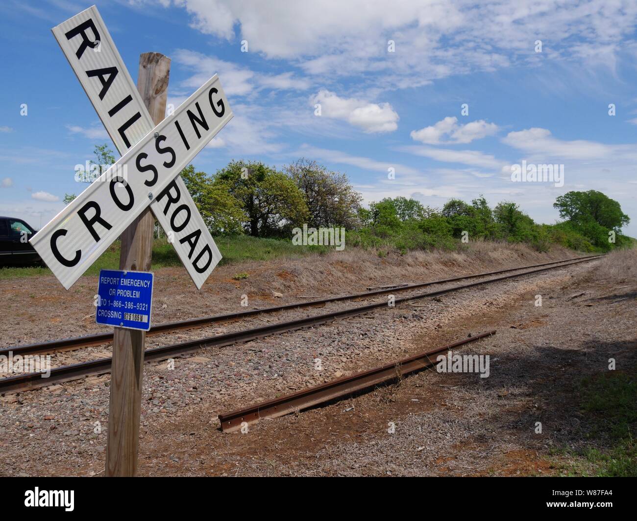 Medium wide shot of a crossing sign at a railroad track Stock Photo - Alamy