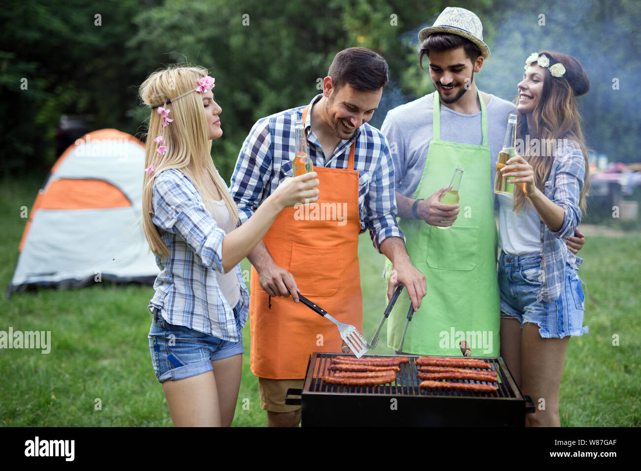Happy group of friends making a barbecue together outdoors in the ...