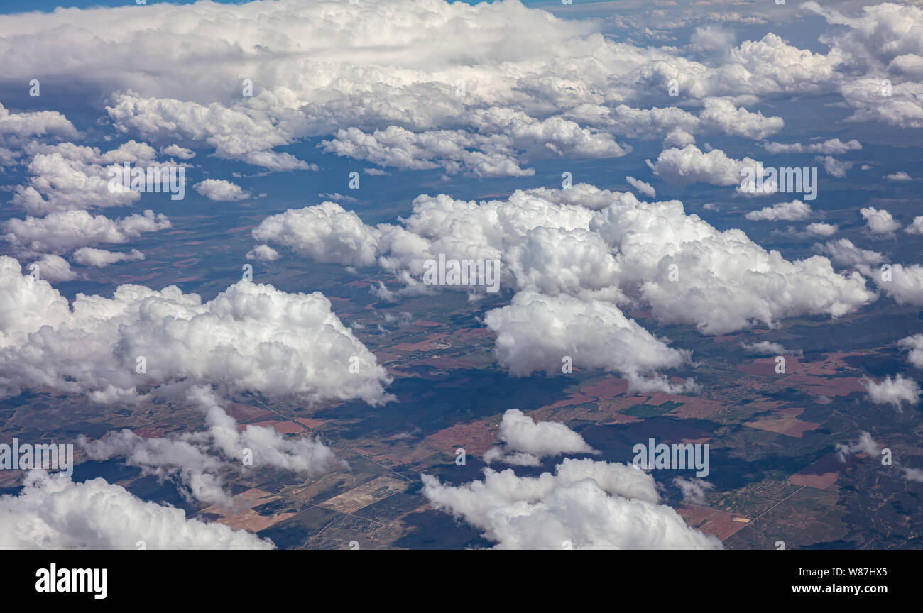 Aerial view out of an airplane window. Agricultural fields and fluffy ...