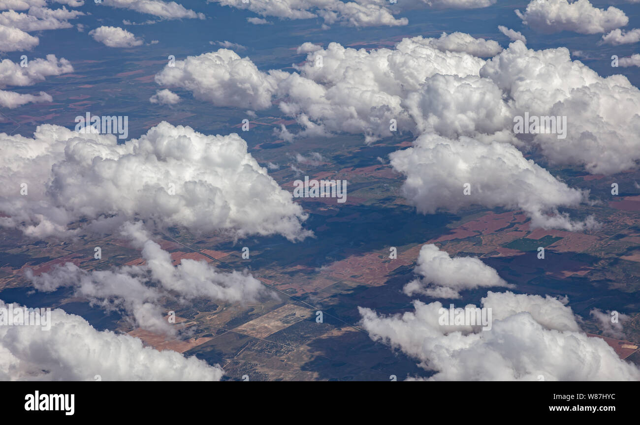Aerial view out of an airplane window. Agricultural fields and fluffy ...
