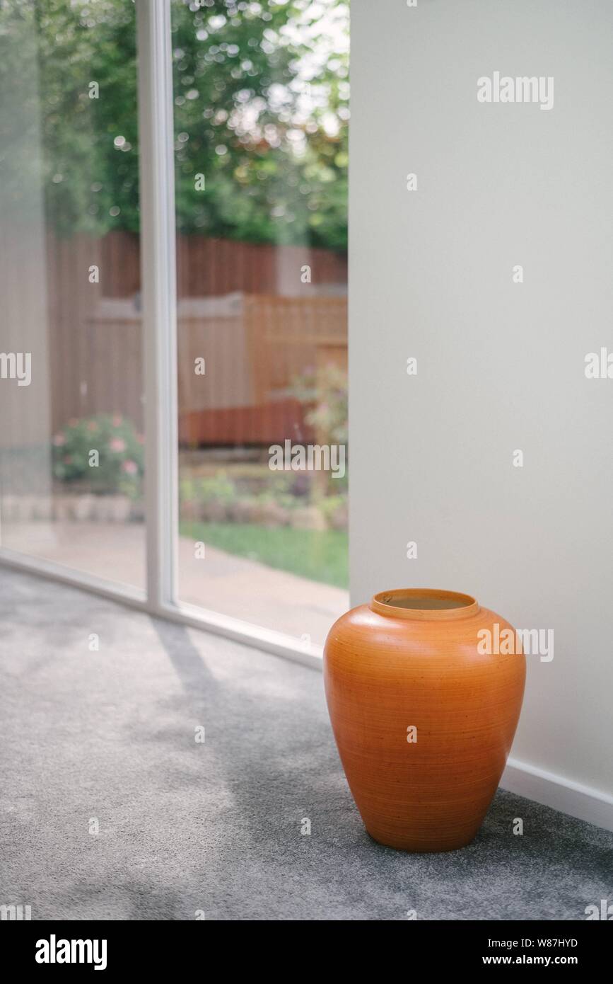 Vertical shot of an orangish vase on the floor near a window Stock ...