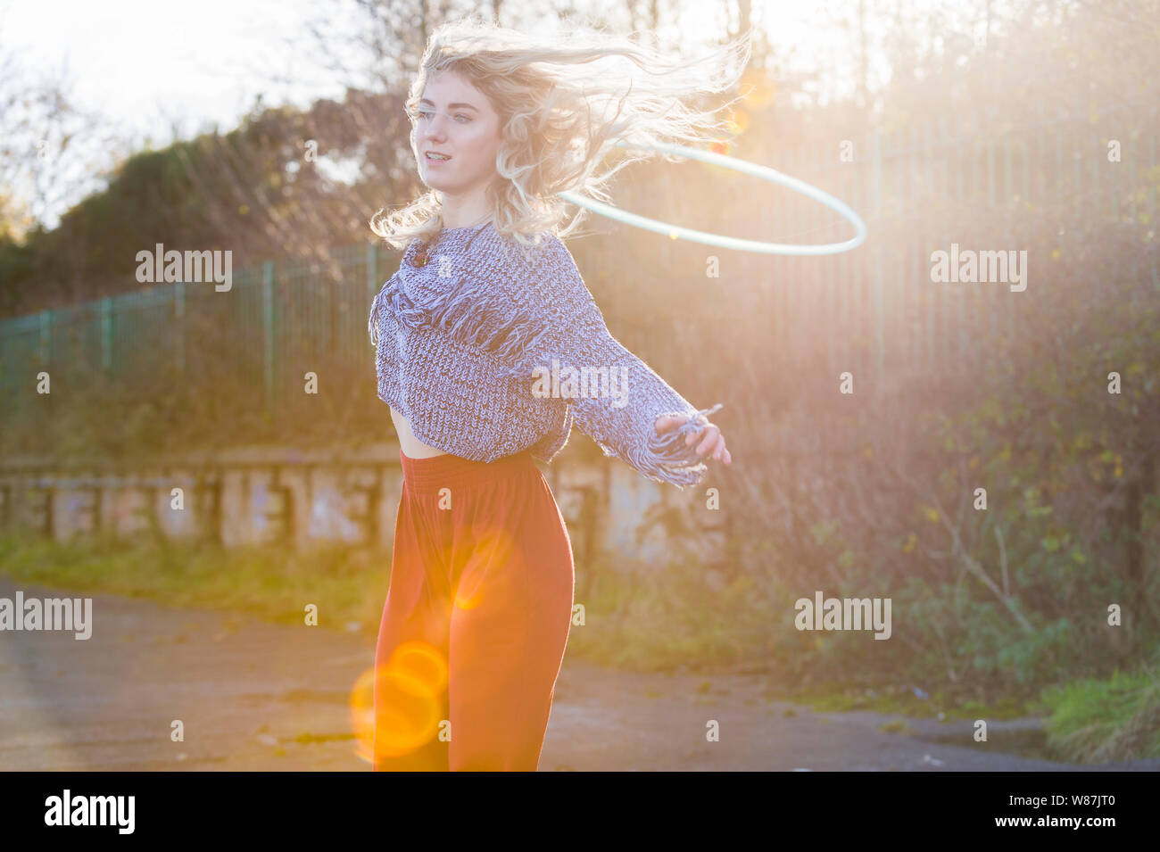 Girl spins around while using a hoop, arms outstretched, three quarter ...