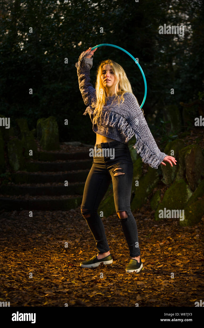 Girl looks forward, in a dramatic pose, holding a hoop over her head ...