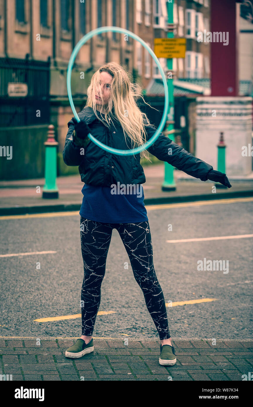 Girl looks up at a spinning hoop, full length body pose, in city street ...