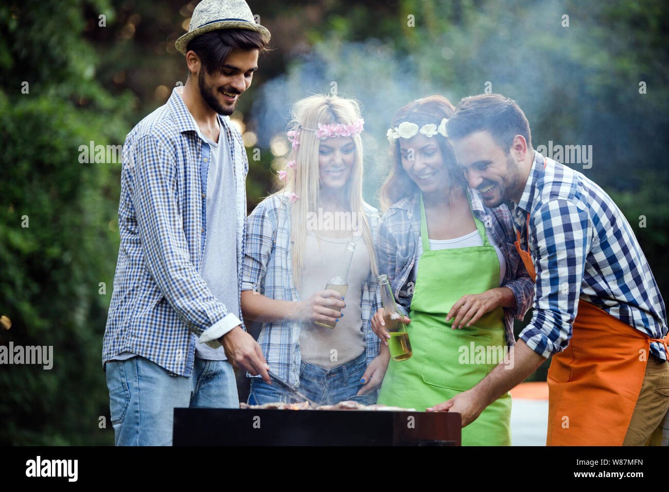 Group of friends making a barbecue together outdoors in the nature ...