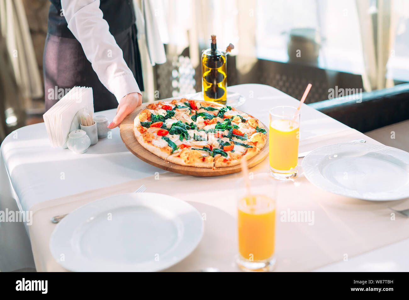 The waiter puts pizza On the table in the Restaurant Stock Photo - Alamy