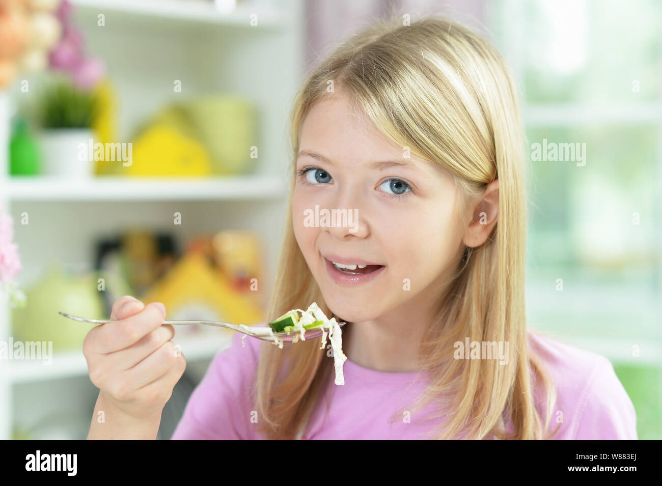Cute girl tasting fresh salad on kitchen table at home Stock Photo - Alamy
