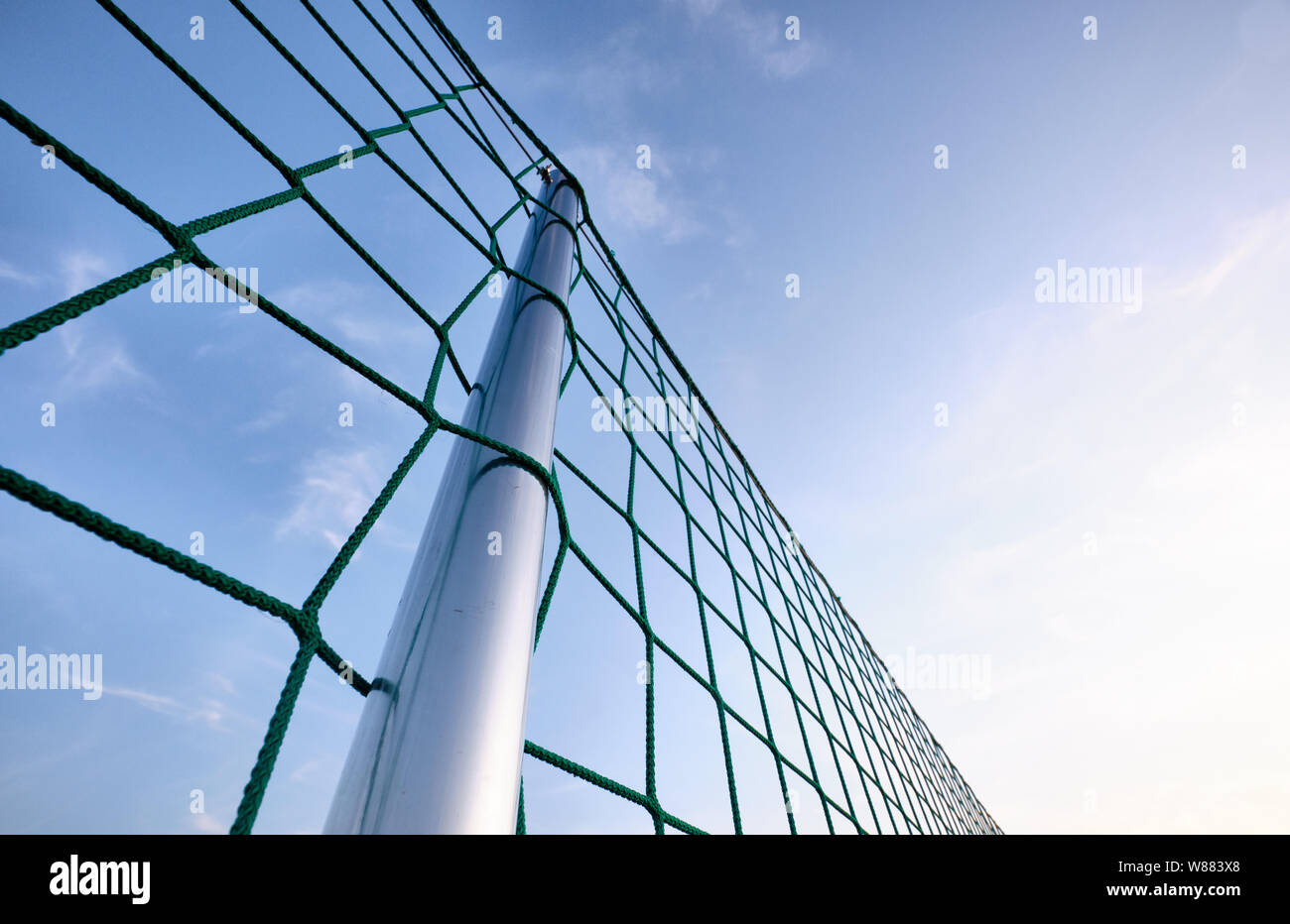 A silver colored pole with a net building a fence against the blue ...