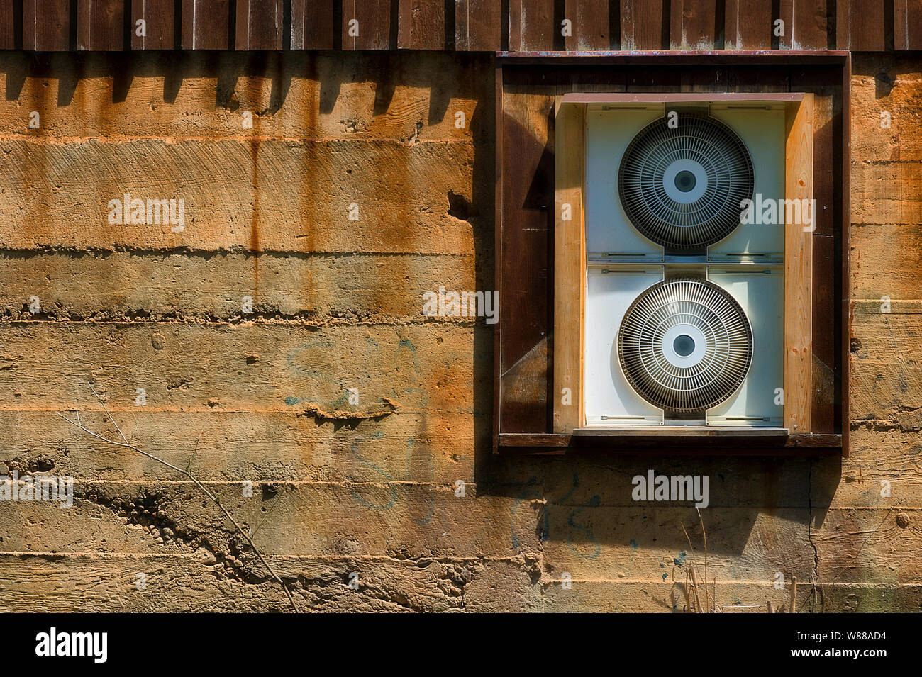 A double fan circulating air on an old exterior wall of a building ...