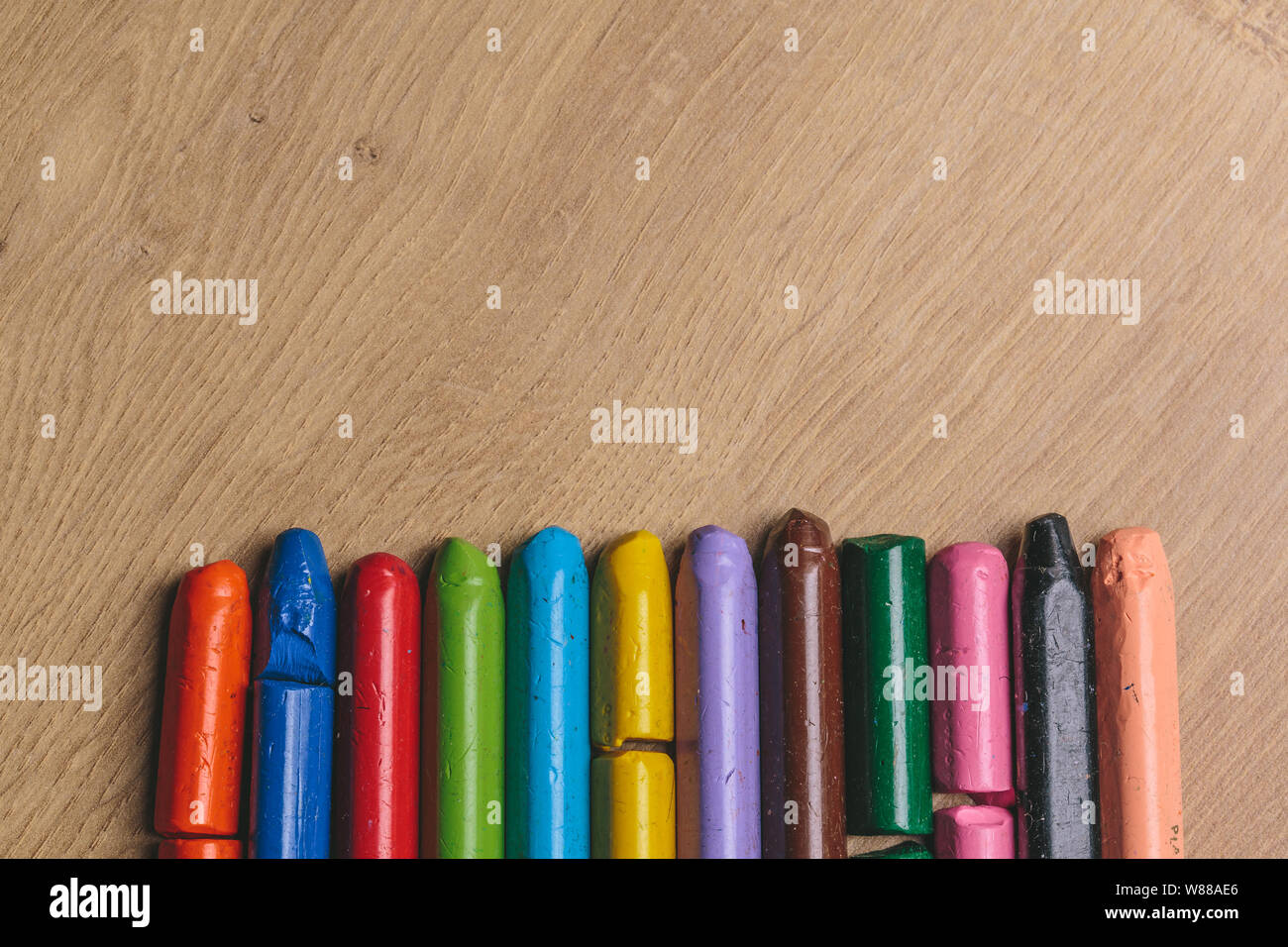 Colourful used crayons in a row on a wooden surface Stock Photo - Alamy