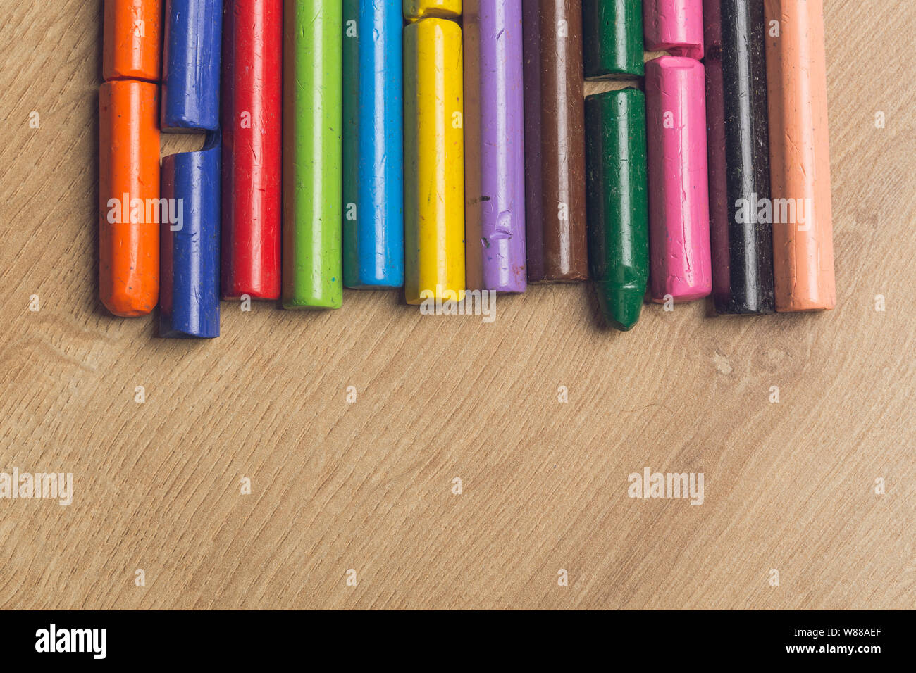 Colourful used crayons in a row on a wooden surface Stock Photo - Alamy