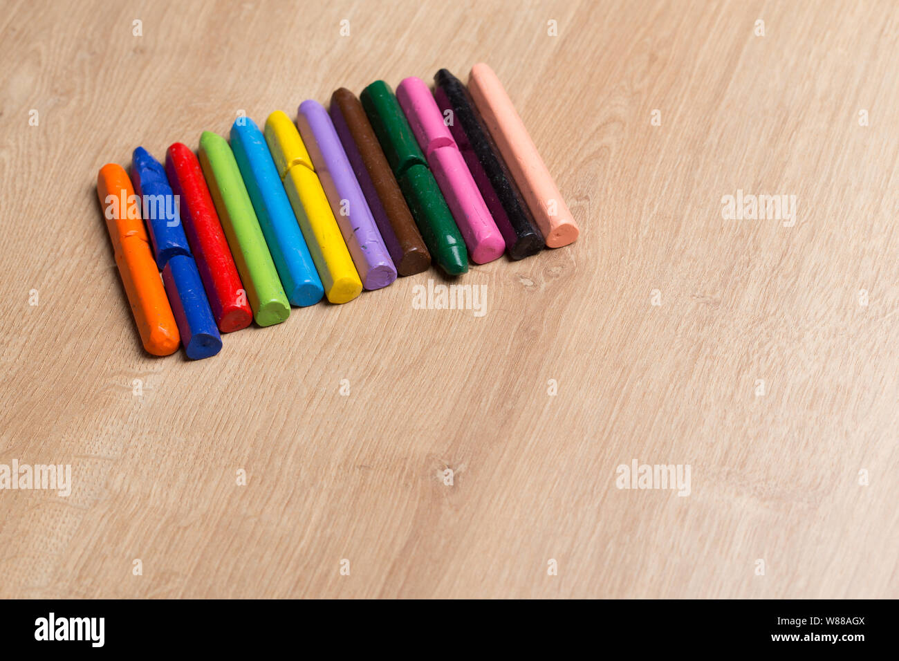 Colourful used crayons in a row on a wooden surface Stock Photo - Alamy