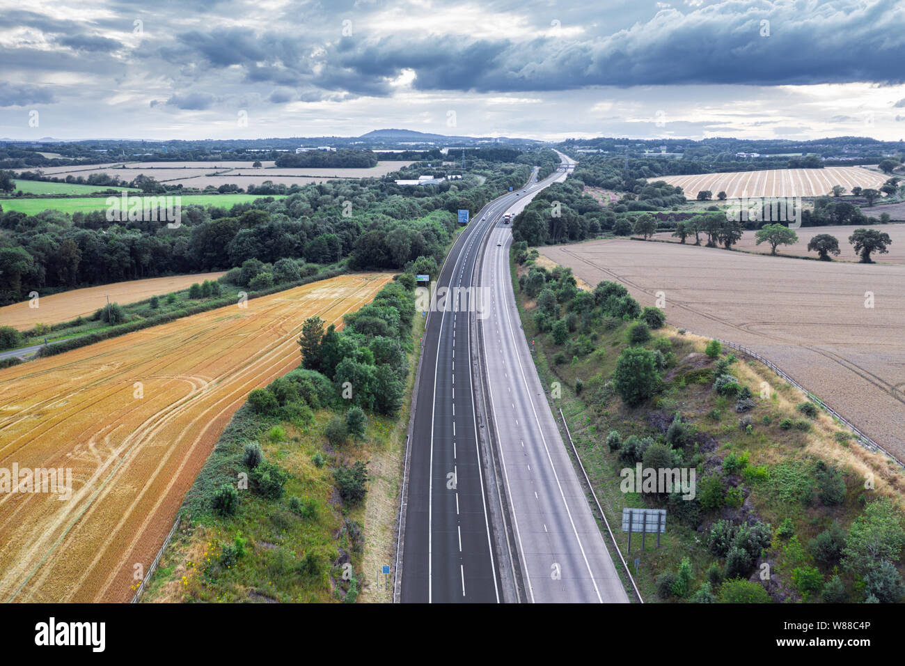 Drone shoot over dual lane motorway M54 across countryside fields at ...