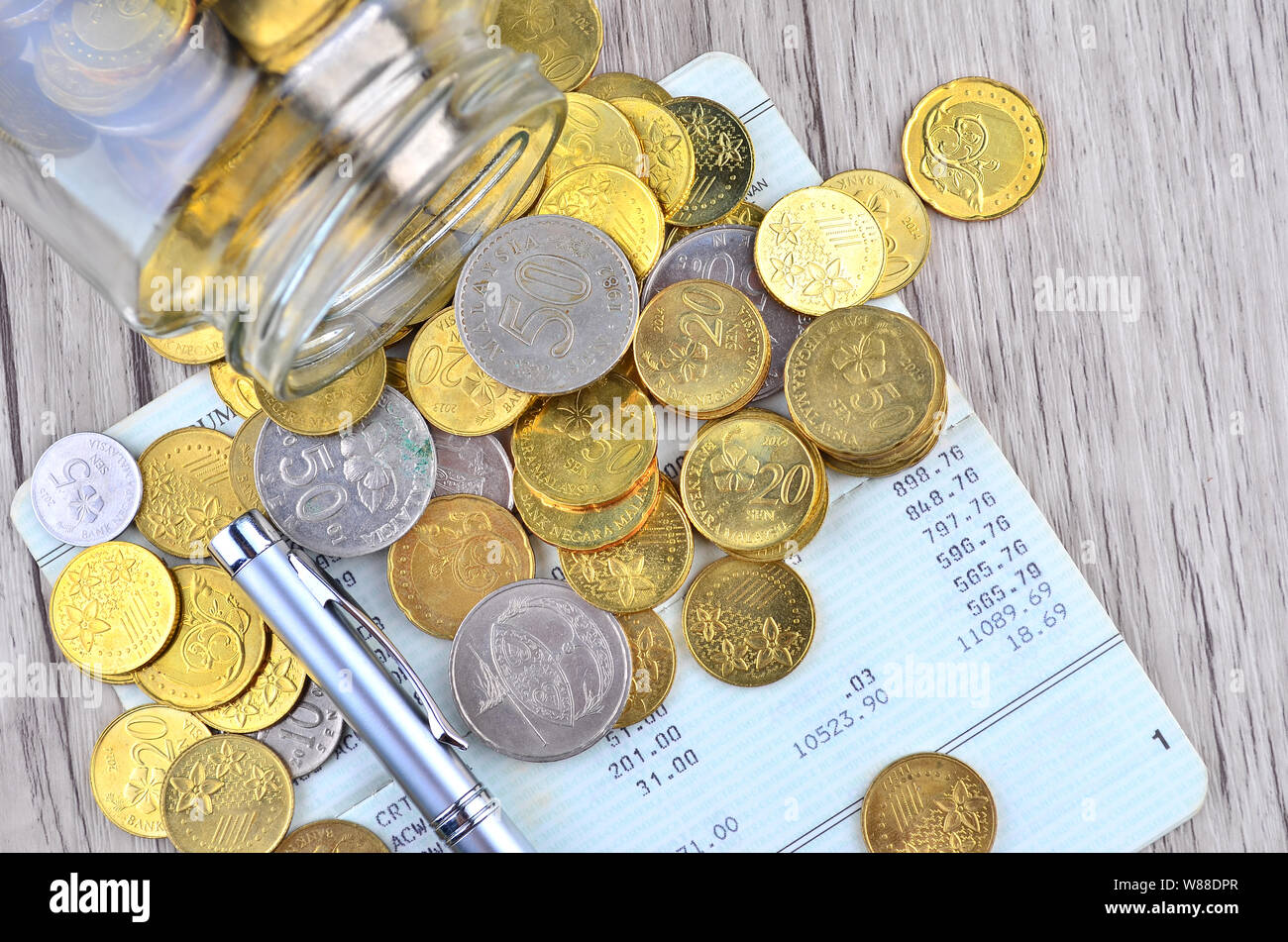 Coins with silver pen on bank account book Stock Photo - Alamy