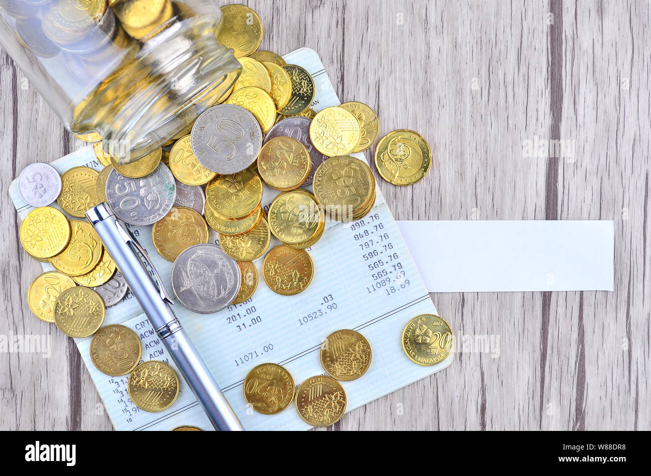 Coins and silver pen on bank account book with blank label Stock Photo ...