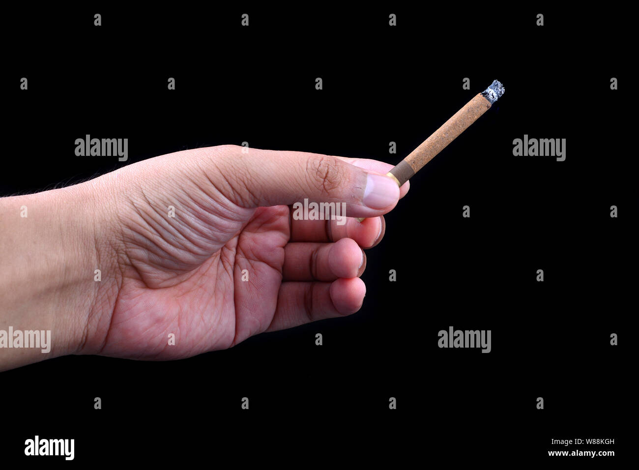 Hand holding cigar on black background Stock Photo - Alamy