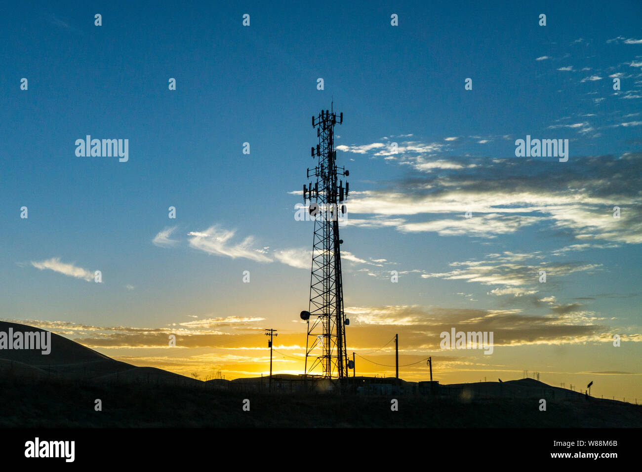 A cell phone communications tower silhouetted by the setting sun in the ...