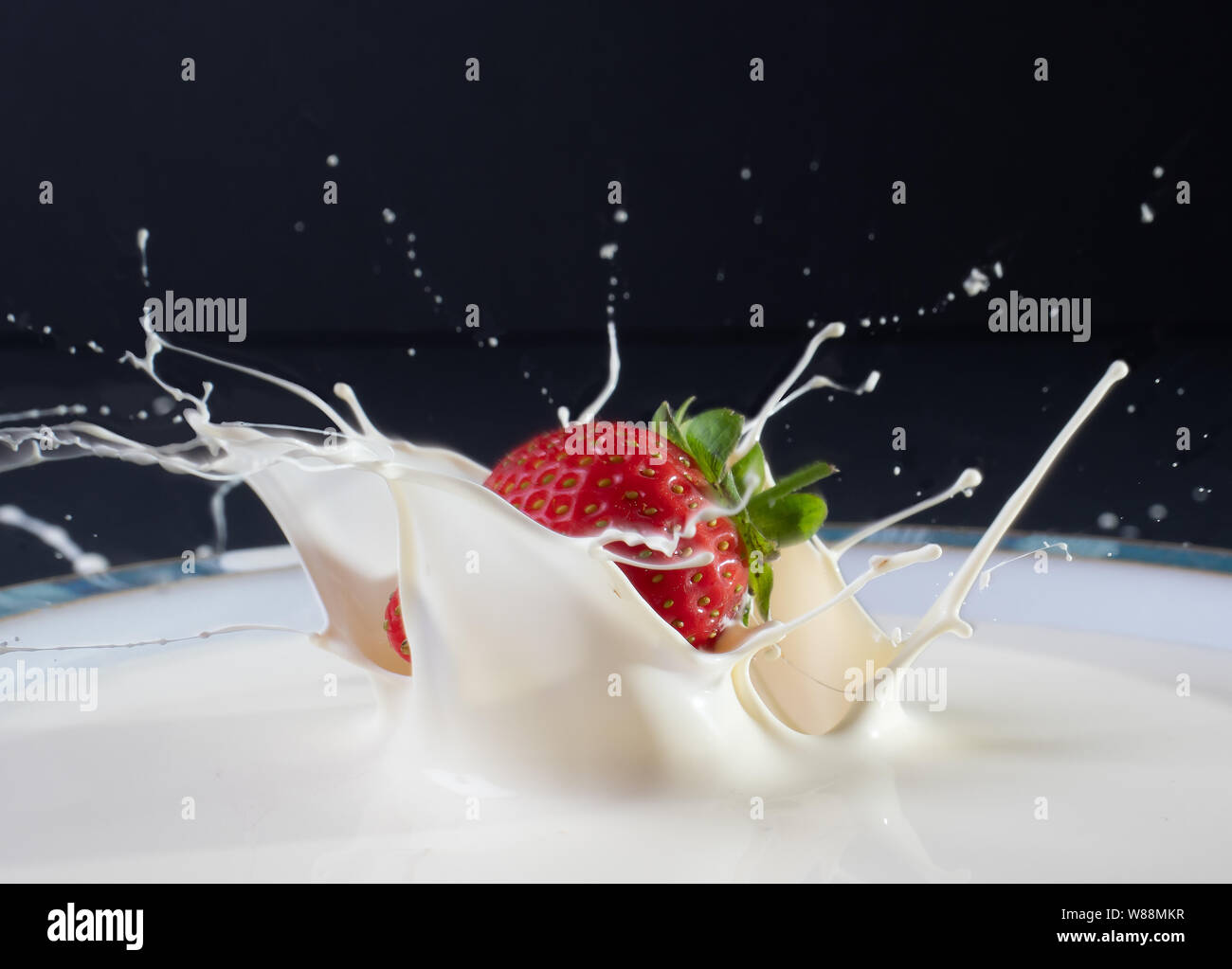 A strawberry splashes into a plate of cream (frozen action Stock Photo ...