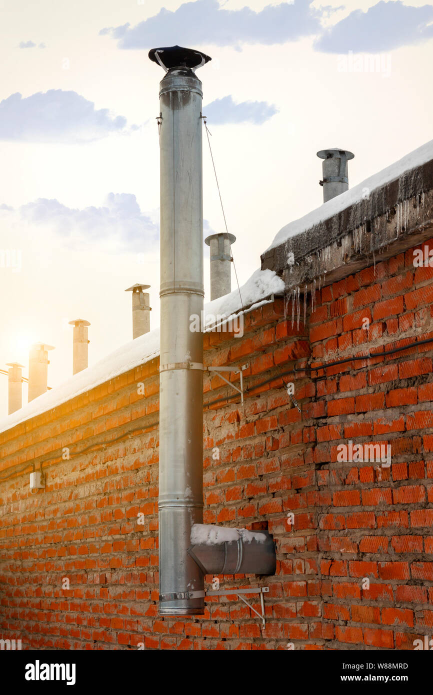 Large metal chimney against the sky and brick wall Stock Photo - Alamy