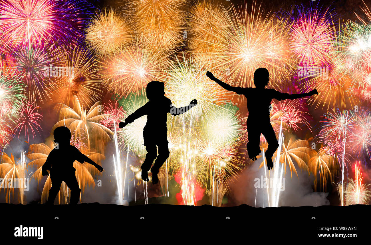Silhouette of kids jumping over colorful firework Stock Photo - Alamy