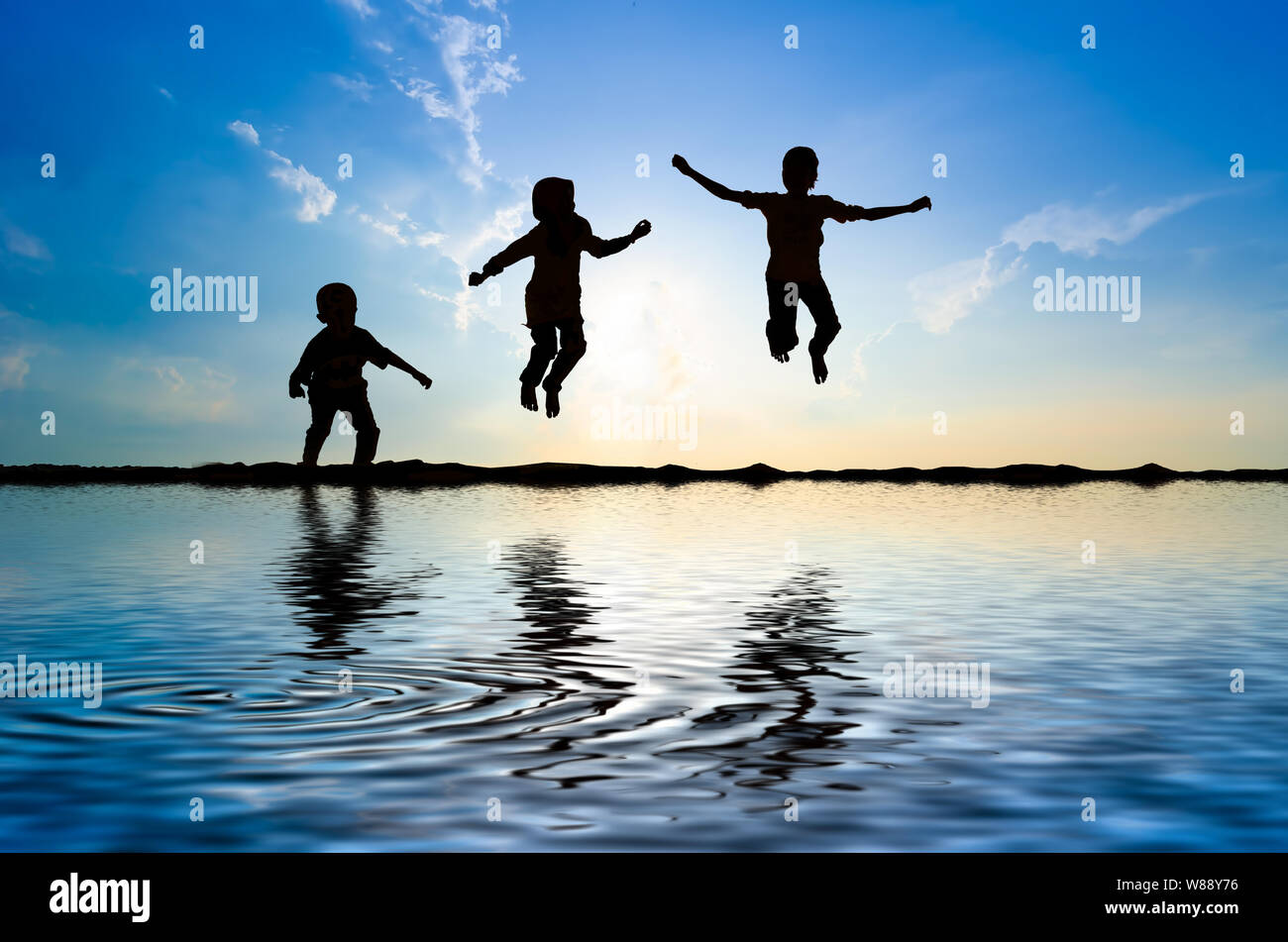 Silhouette of kids jumping over sun rising up Stock Photo - Alamy