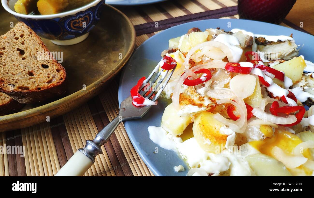 Closeup of breakfast dish, baked fish and potatoes with pickles ...