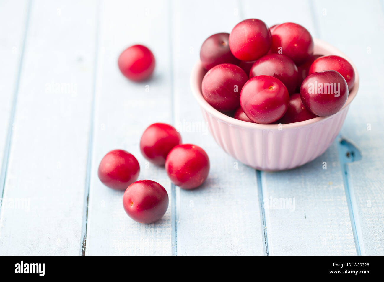 The red cherry plums fruit on blue table Stock Photo - Alamy