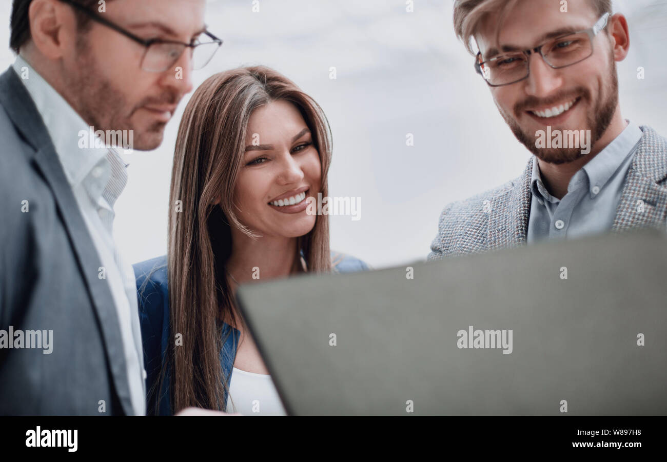 close up. smiling business team looks at the laptop screen Stock Photo ...
