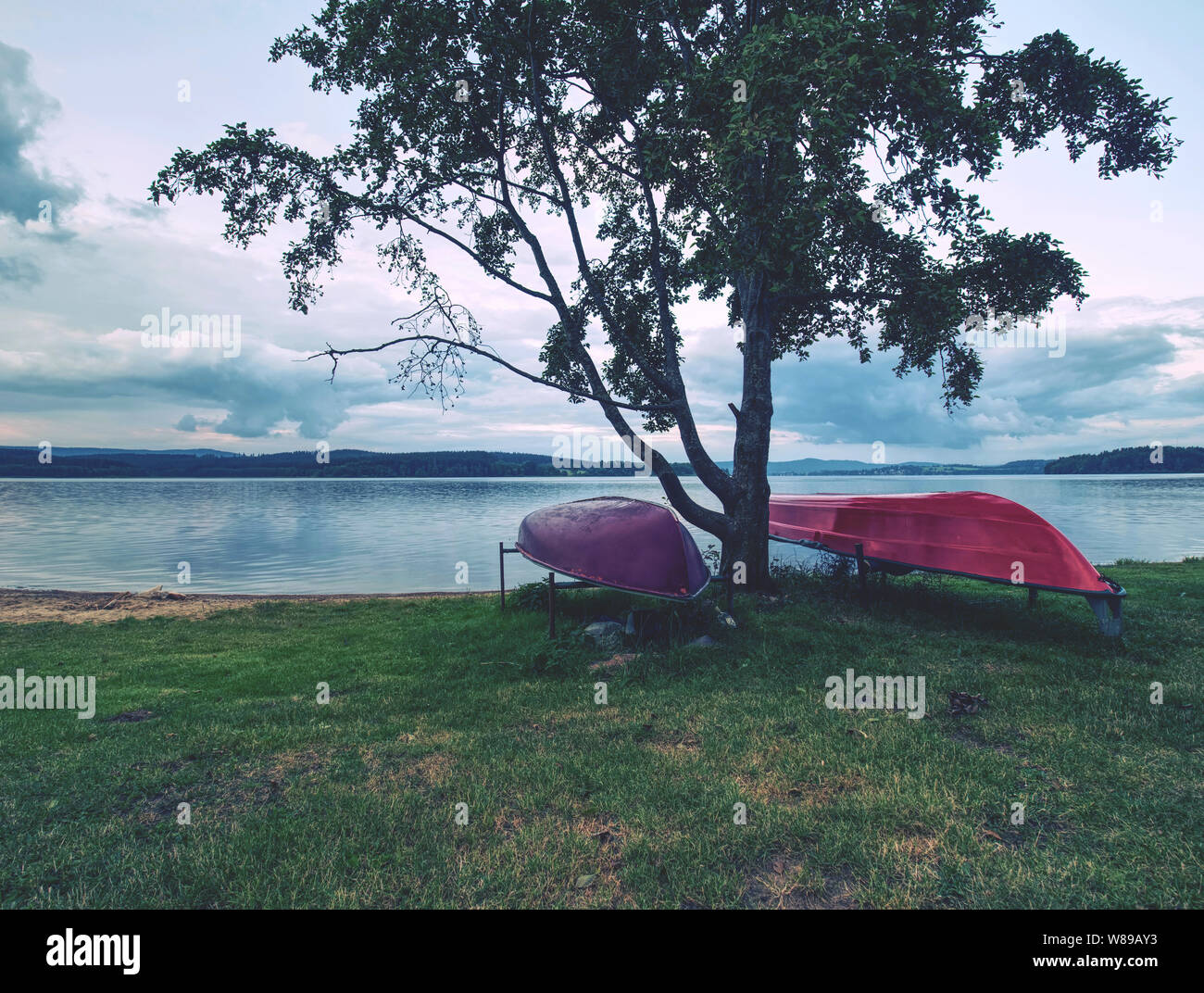 Simple rowing boat stacked at lake upside down. Empty beach at popular ...
