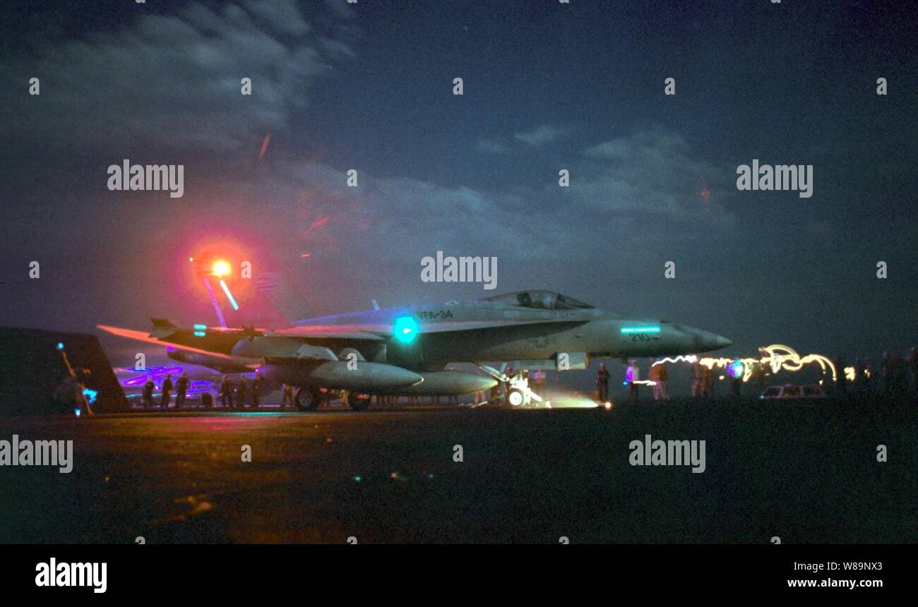 An F/A-18C Hornet is prepared for a night catapult launch from the ...