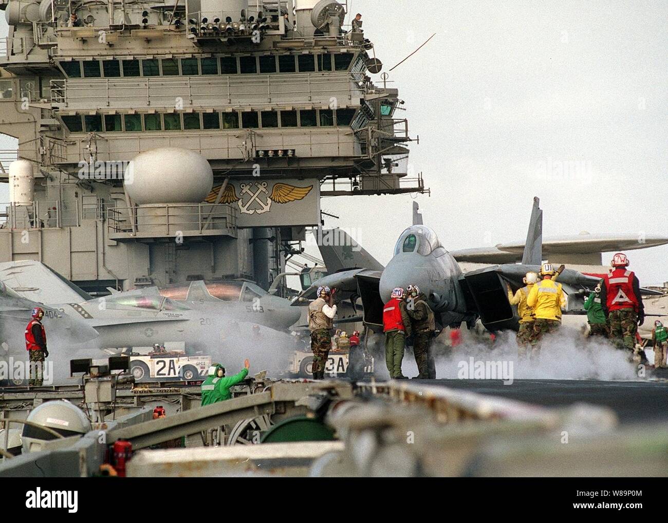 Steam rises from a previous catapult launch as an F-14 Tomcat is ...