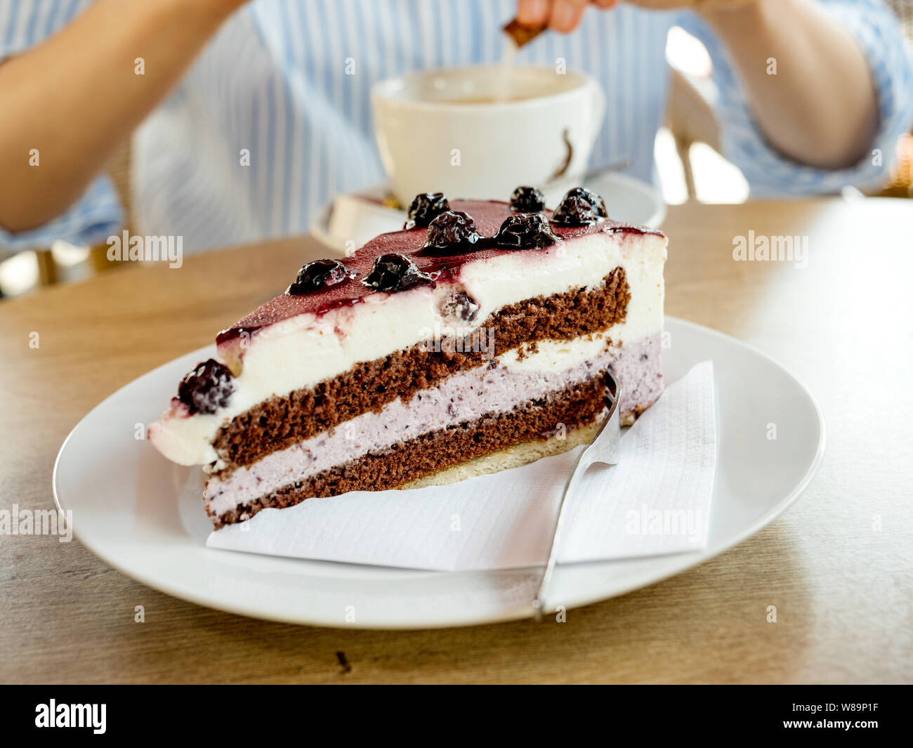Delicious German cake Schwarzwald kirshetarten with woman pouring sugar ...