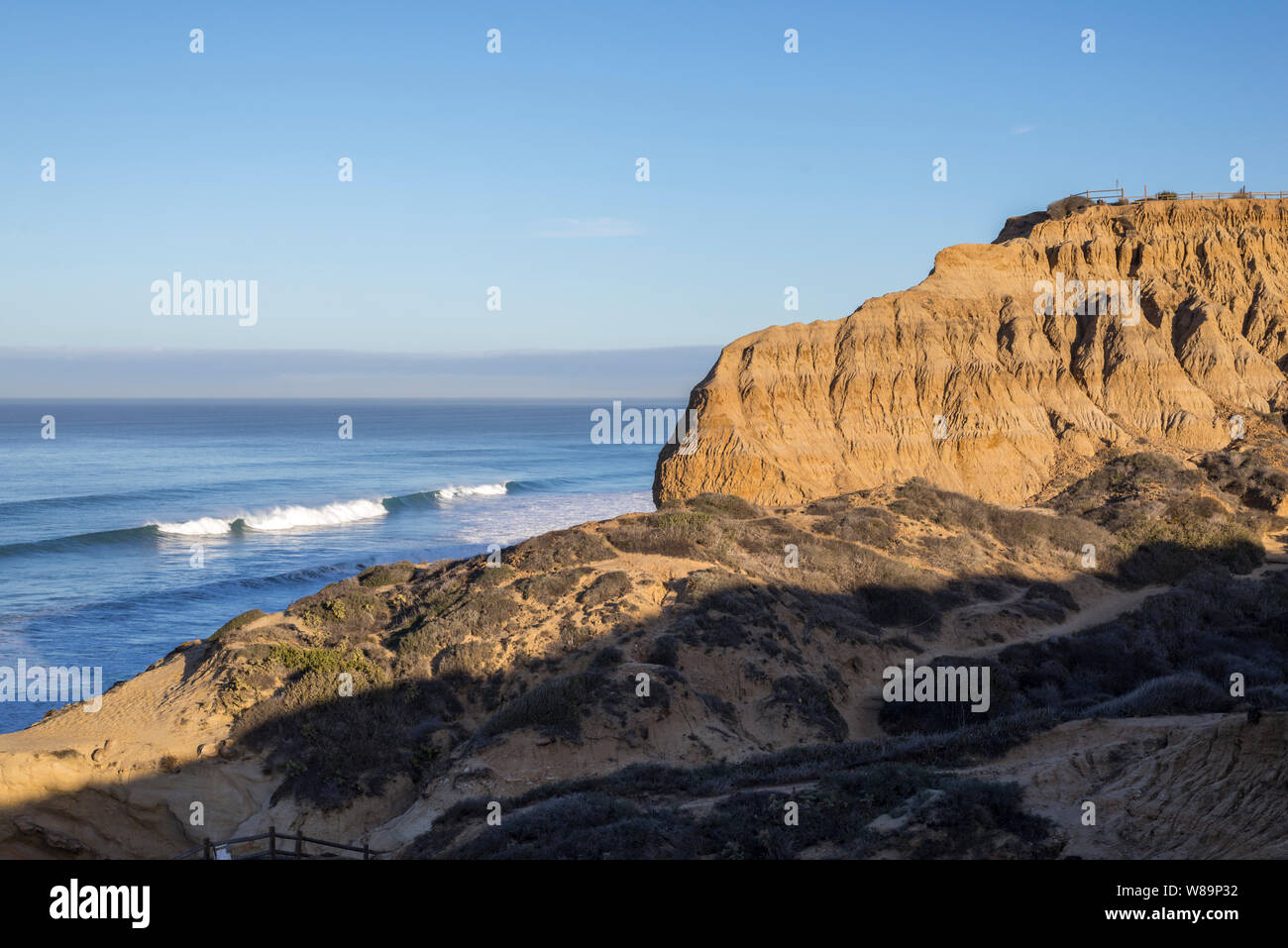 The rising Sun illuminating sandstone cliffs above the ocean. Torrey ...